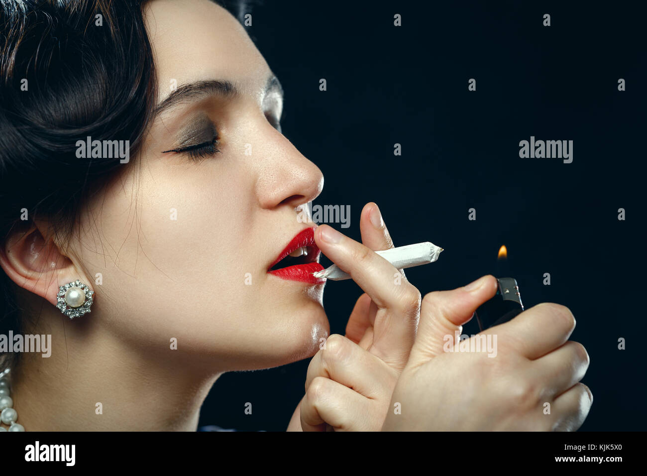 blond young woman smoking joint on black background Stock Photo - Alamy