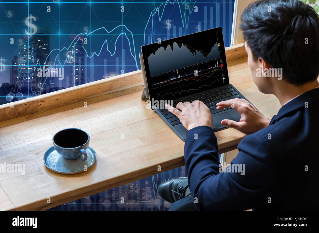 Businessman sitting and using computer laptop showing trading graph ...