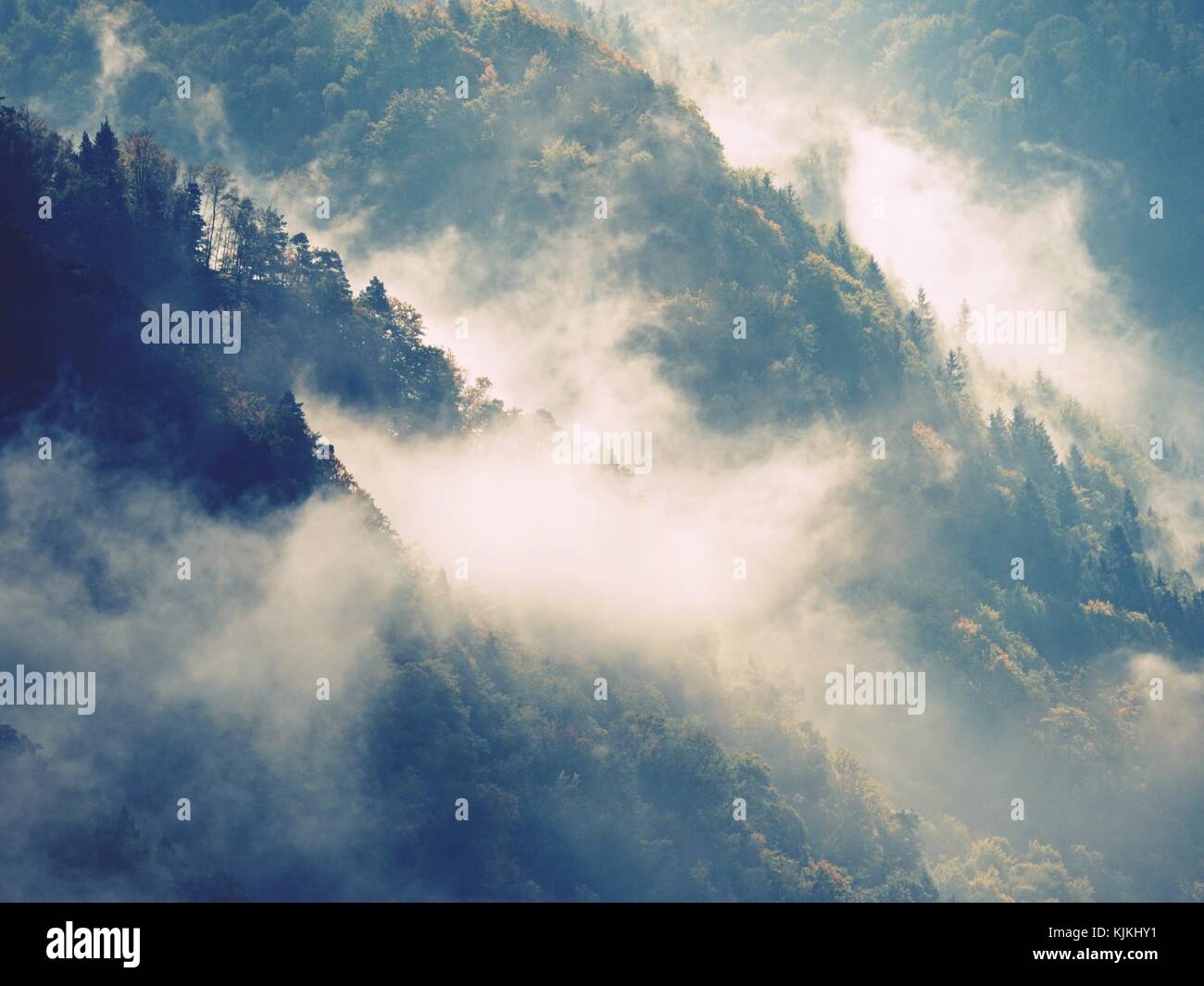 Cold and damp morning in autumn nature. Outlines of forest hills hidden ...