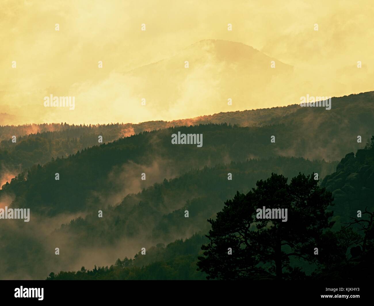 Cold and damp morning in autumn nature. Outlines of forest hills hidden ...