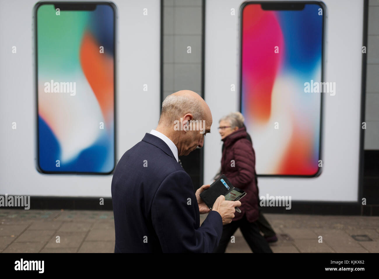 A man uses his handset while walking past an ad for the new Apple ...