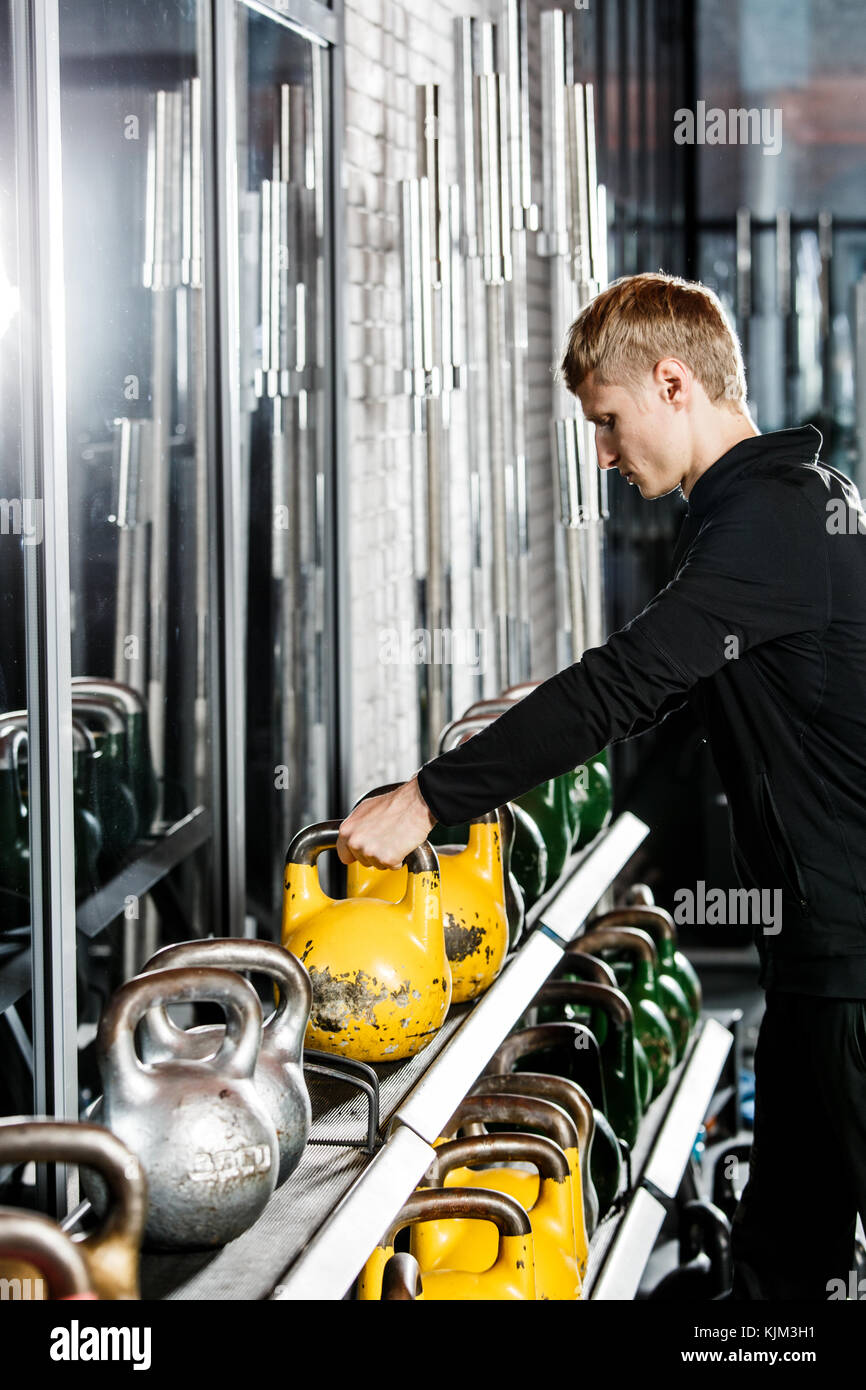 guy removes yellow weights after training in the gym on the window ...