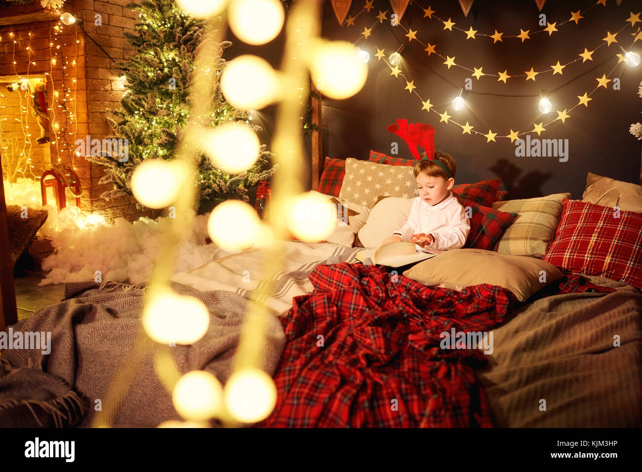 A child little boy is reading a book in the Christmas room Stock Photo ...