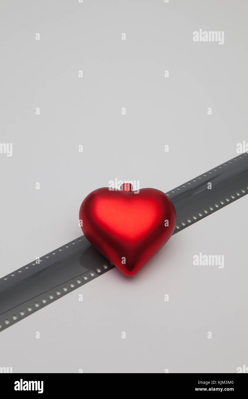 The red heart and the unrolled exposed 35mm film strips over a white ...