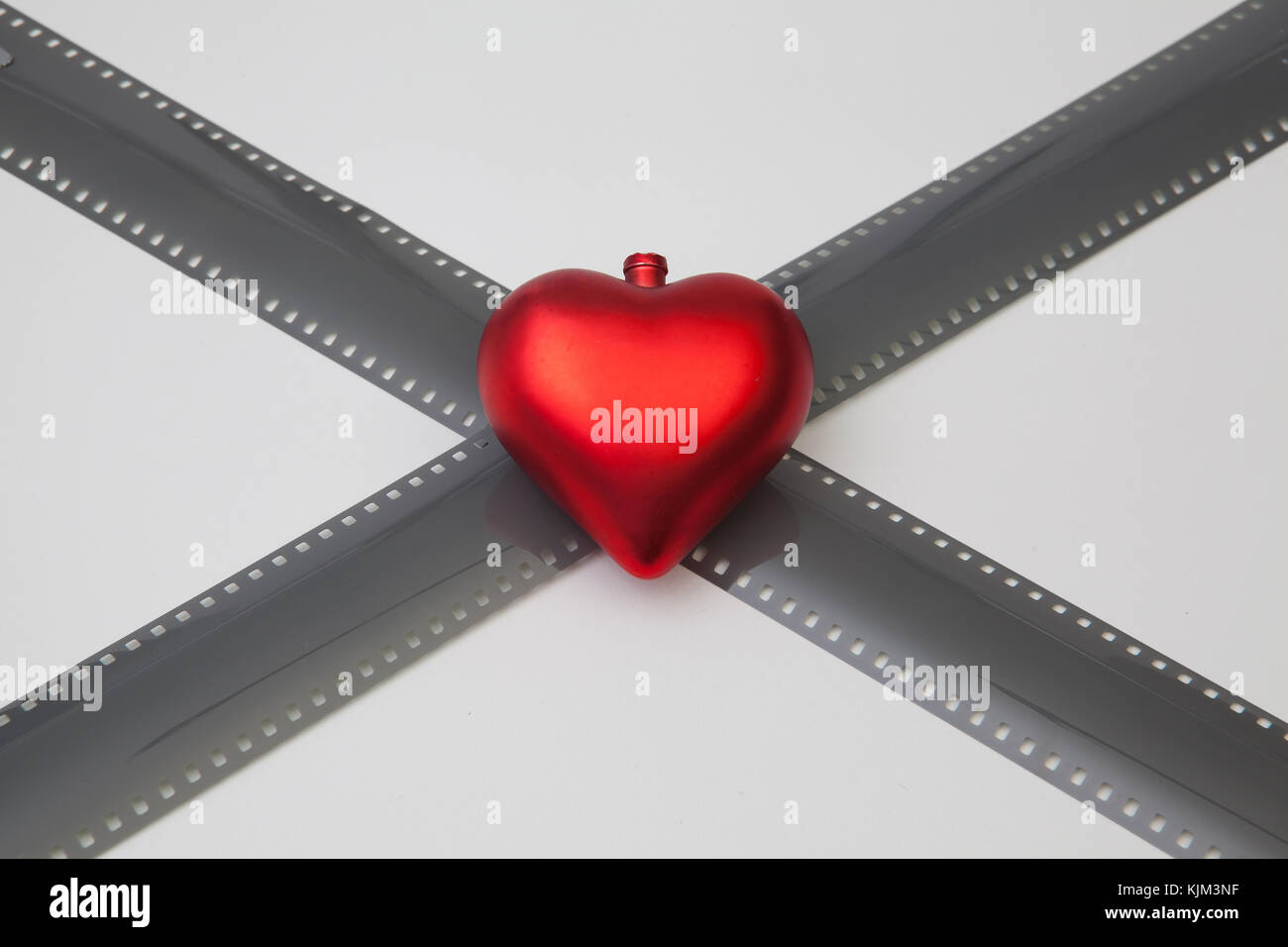 The red heart and the unrolled exposed 35mm film strips over a white ...