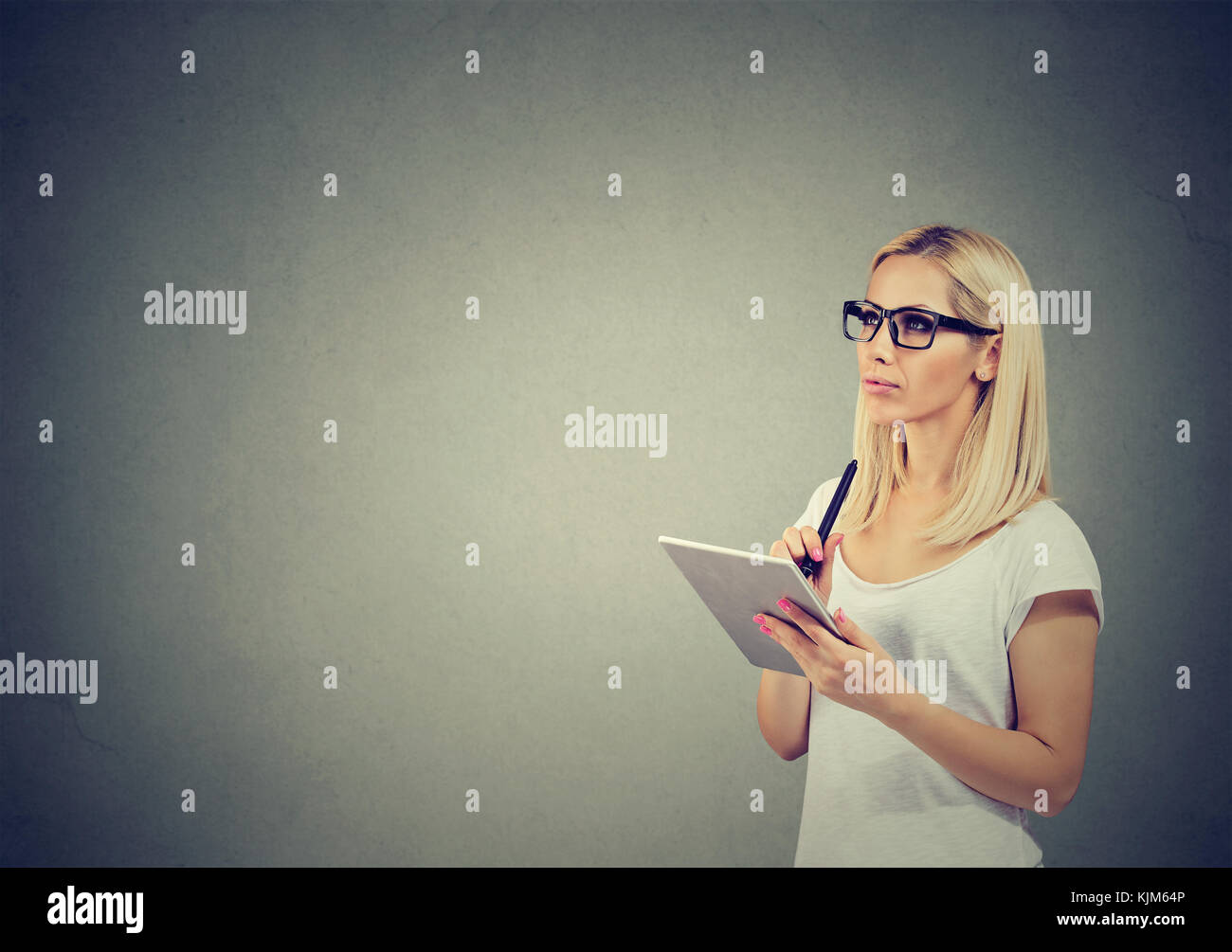 Thoughtful young woman with tablet computer planning Stock Photo - Alamy