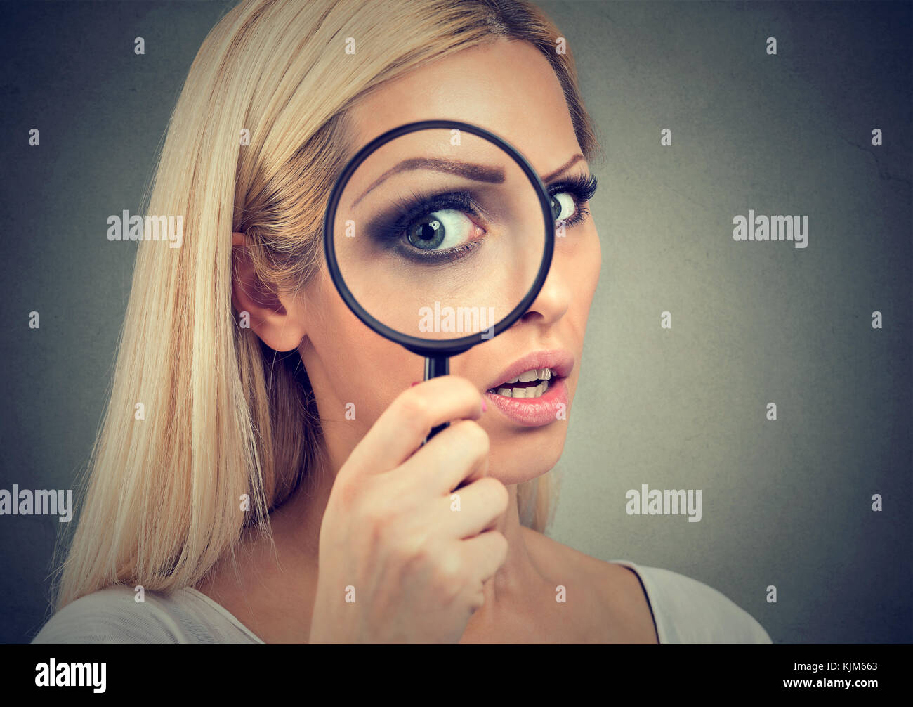 Curious woman looking through a magnifying glass Stock Photo - Alamy