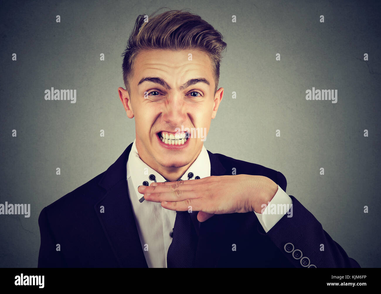 angry young man gesturing with hand to stop talking, cut it out ...