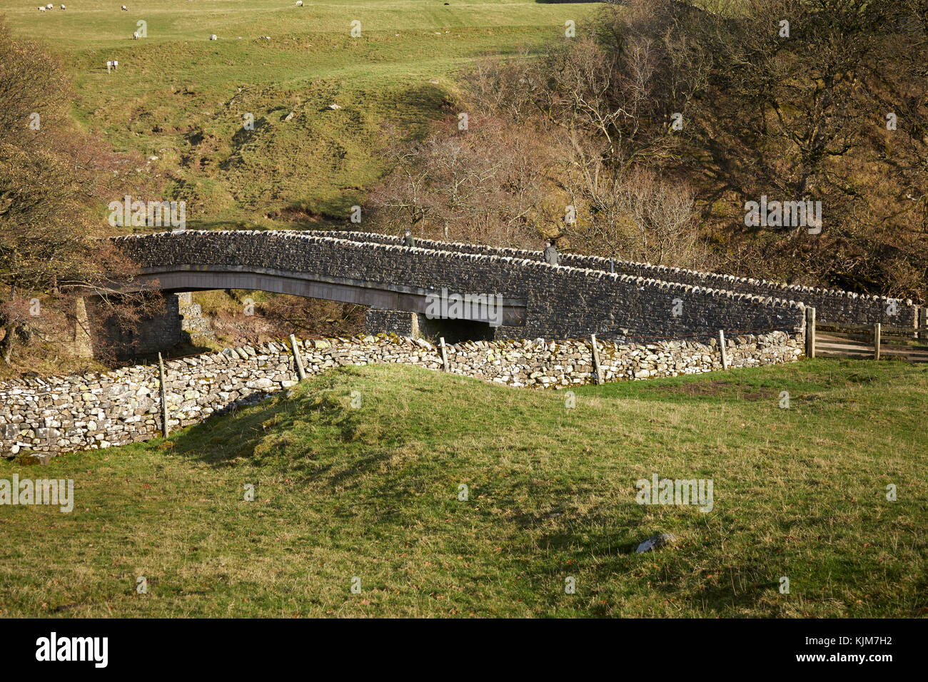 In afternoon autumn sunshine a concrete slab bridge with stonework ...