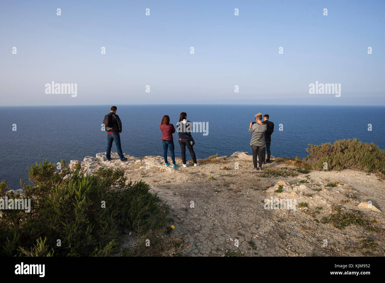 Group of people on the top of the cliff, overlooking at sea Stock Photo ...