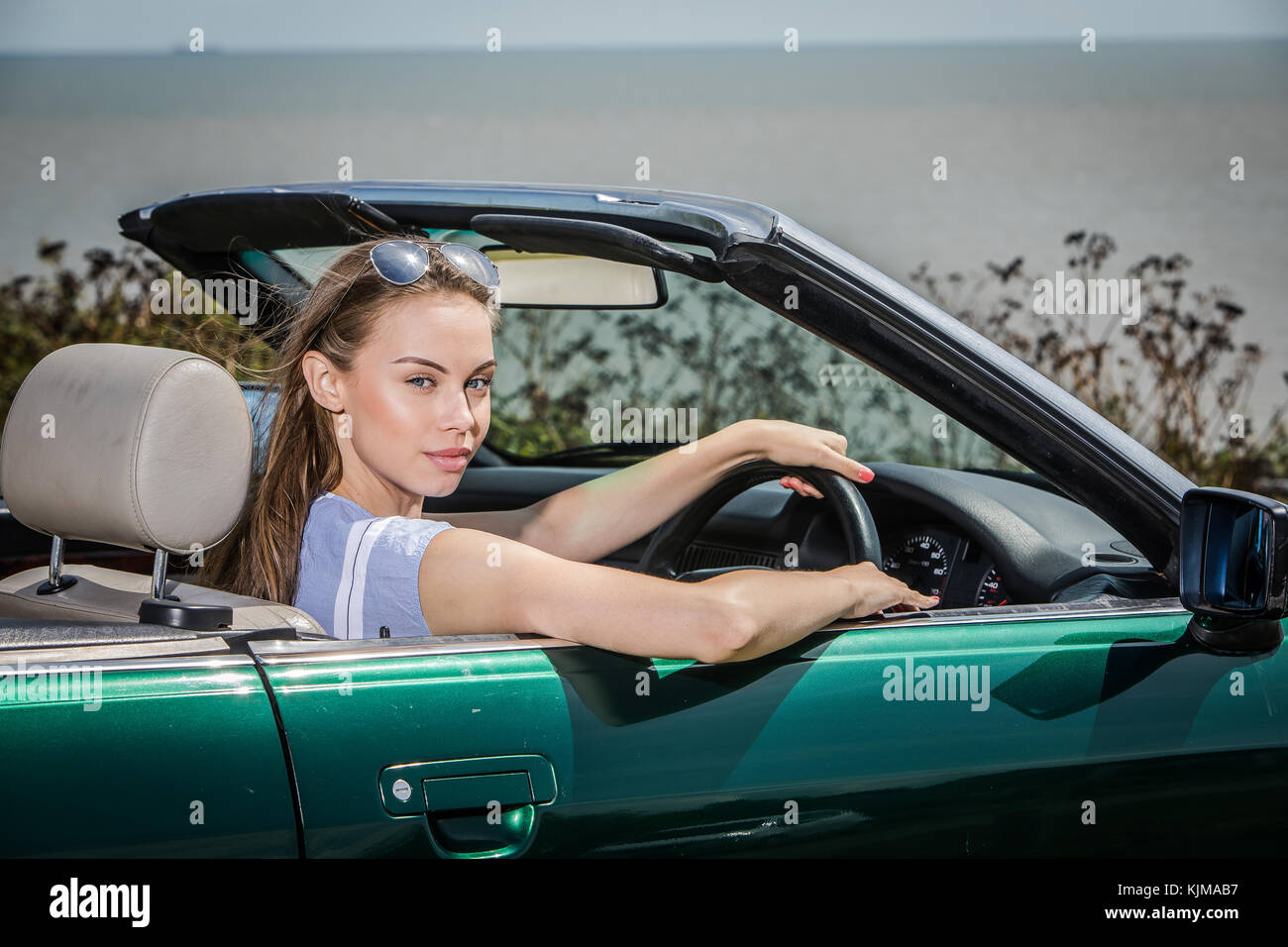 A beautiful young woman Driving her convertible car on a summer road ...