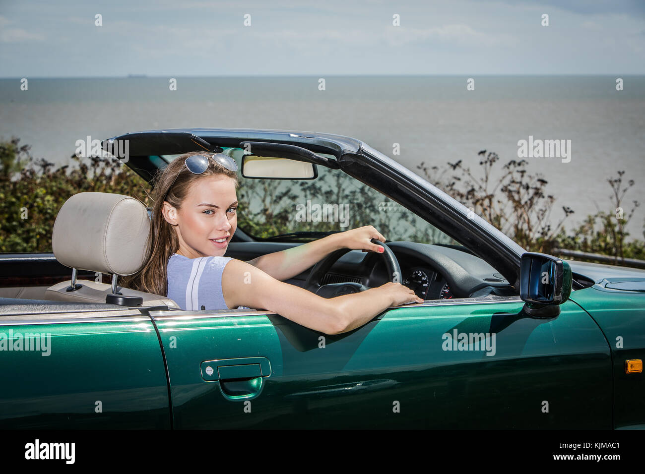 A beautiful young woman Driving her convertible car on a summer road ...