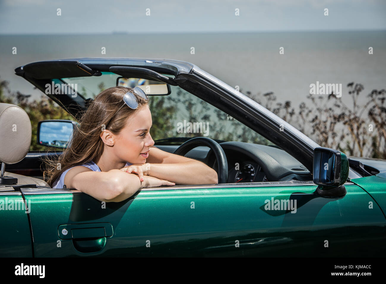 A beautiful young woman Driving her convertible car on a summer road ...