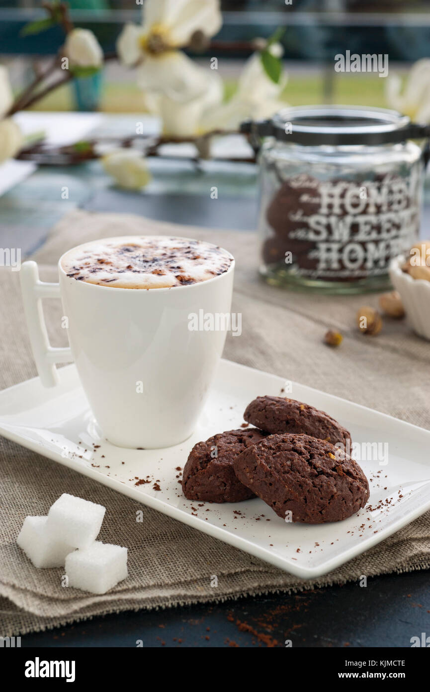 rustic cookies with cocoa and pistachios on white tray, ceramic foam ...
