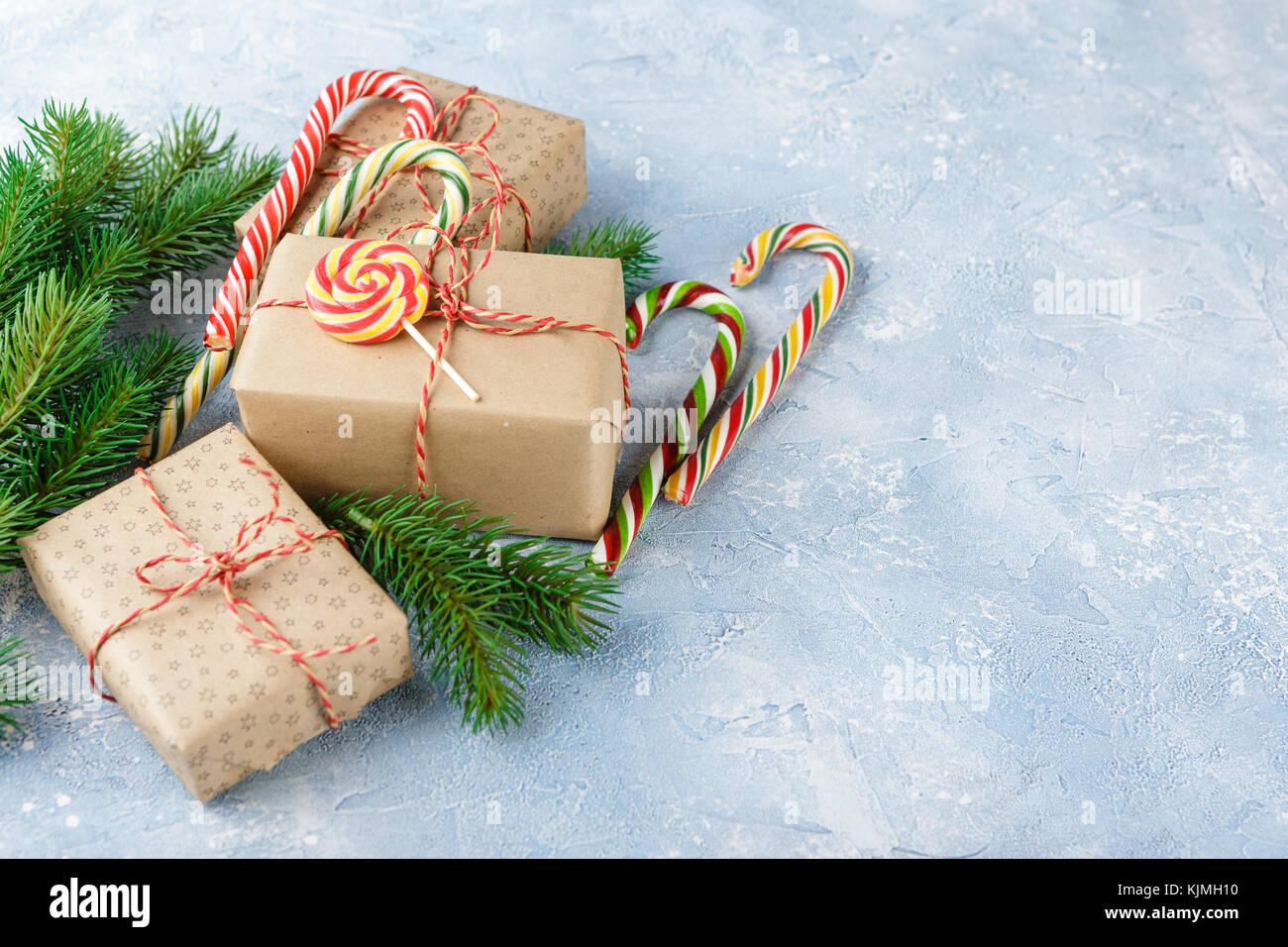 Gift boxes in kraft paper, candy canes and branch of Christmas trees on ...