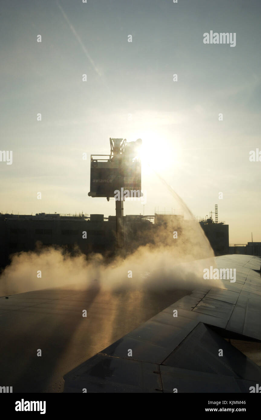A man standing on a cherry picker platform, spraying de-icing fluid on ...
