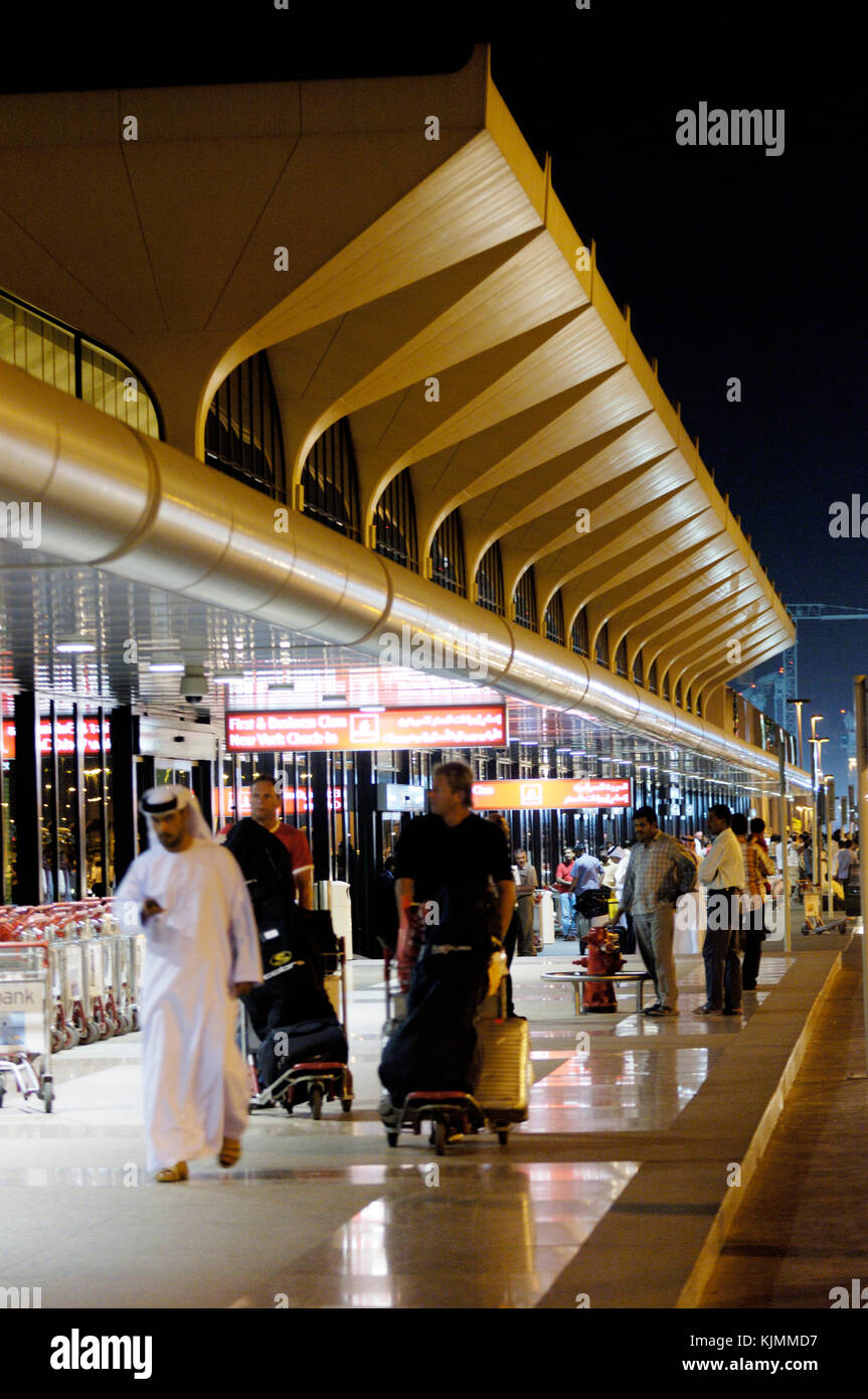 Arab businessmen and men with baggage trolley walking past Terminal1 ...
