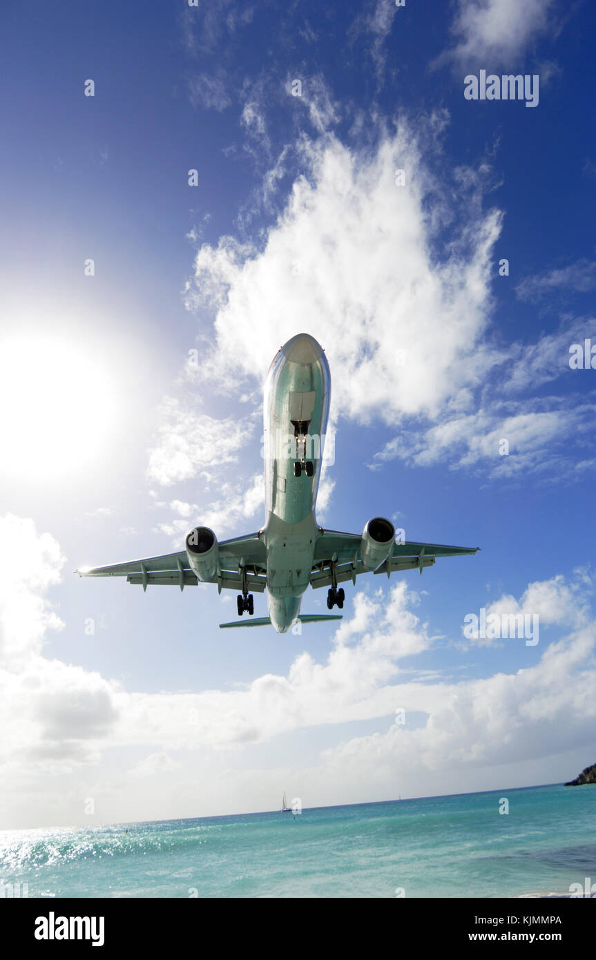 flying low on final-approach landing over the sea at Maho Beach Stock ...
