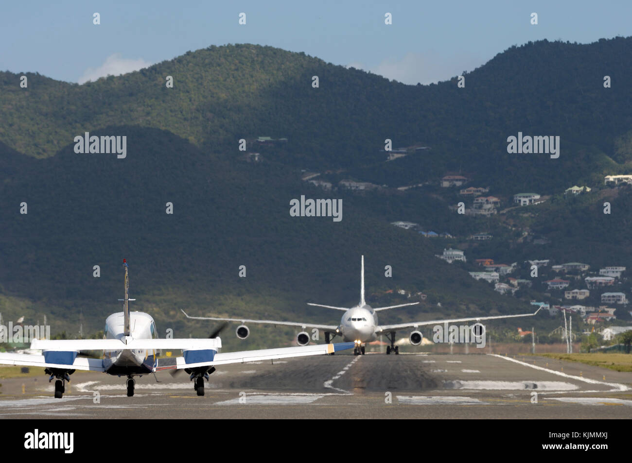 An Airbus A340 taxiing backtracking the runway with a Piper Aztec jet ...