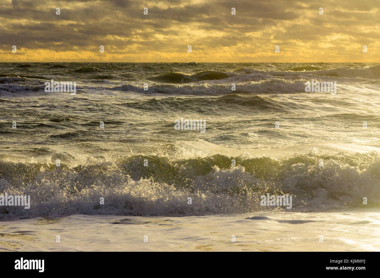 Small waves in the troubled sea roll on the shore with foam under the ...