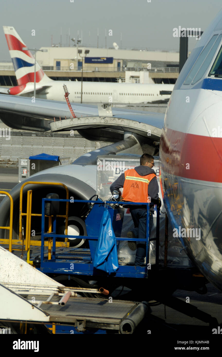 Man wearing an orange high-viz tabard loading an LD3 baggage container ...