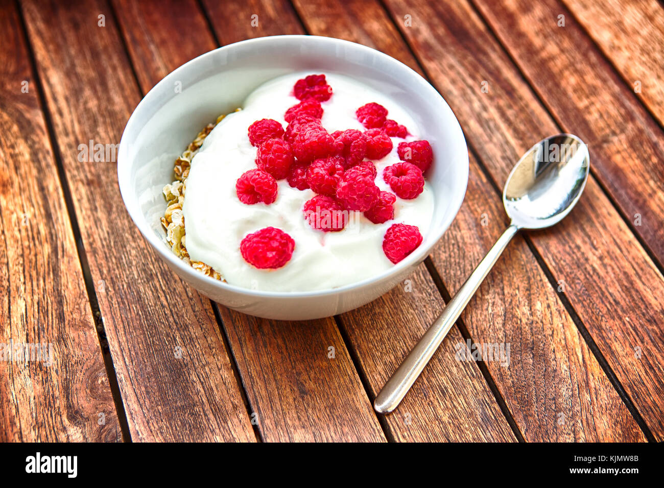 bowl of raspberries with yogurt on wooden table Stock Photo - Alamy