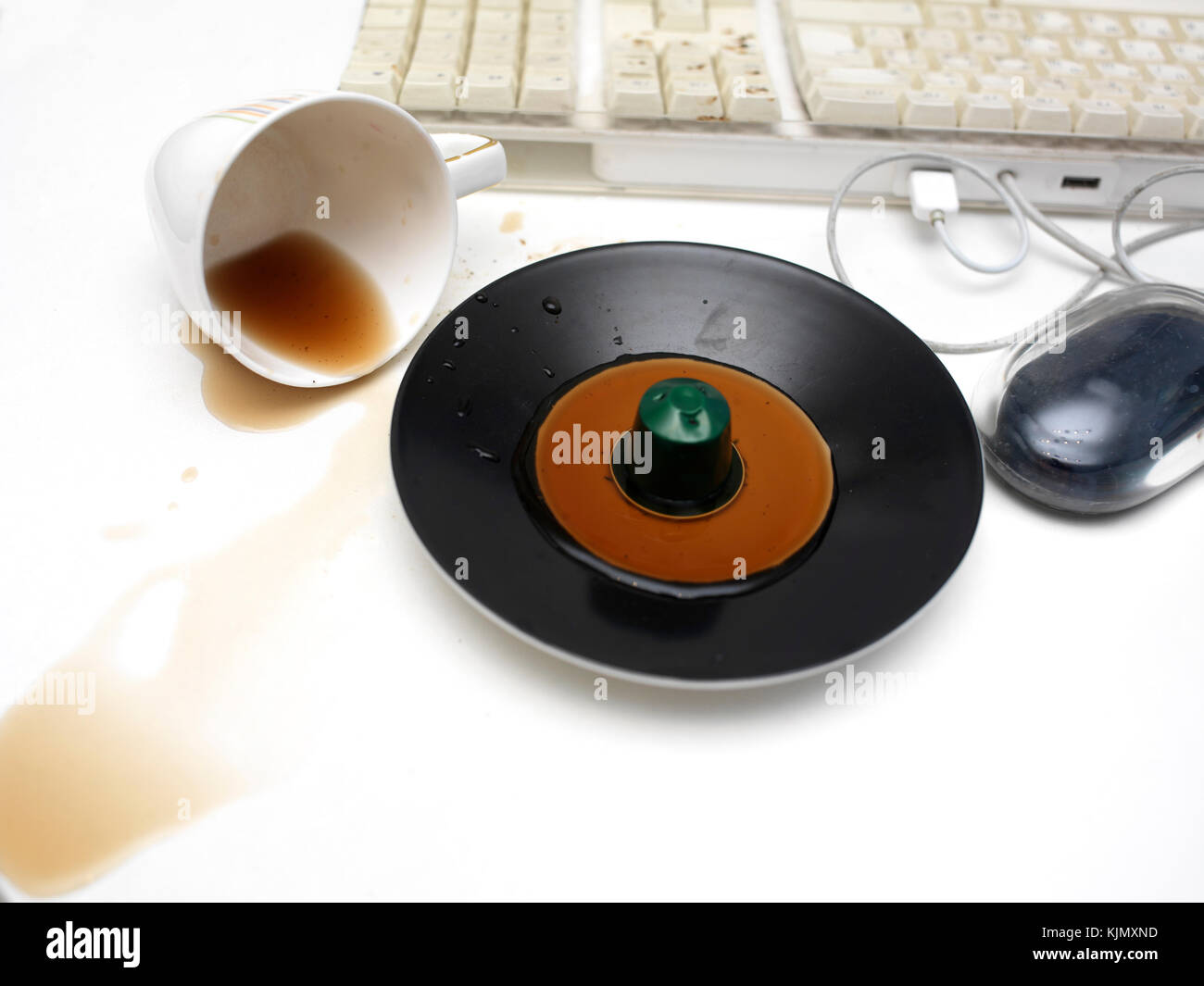 A coffee spilled next to the computer keyboard, concept of untidiness ...