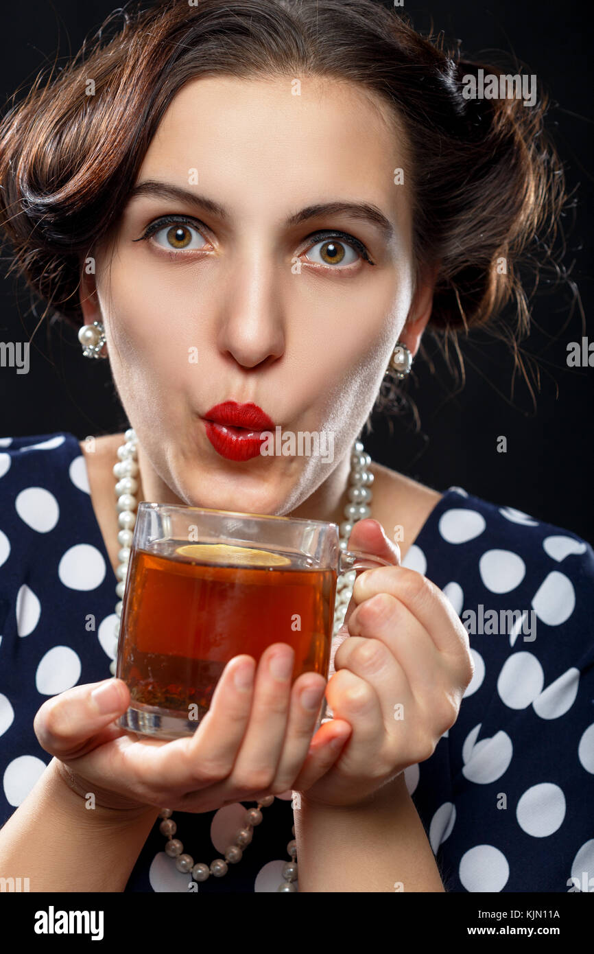 beautiful pinup woman with cup of tea on black background looking at ...