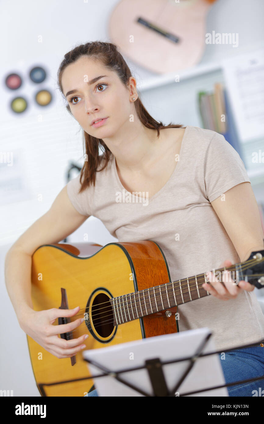 young woman holding guitar and learning to play song Stock Photo - Alamy