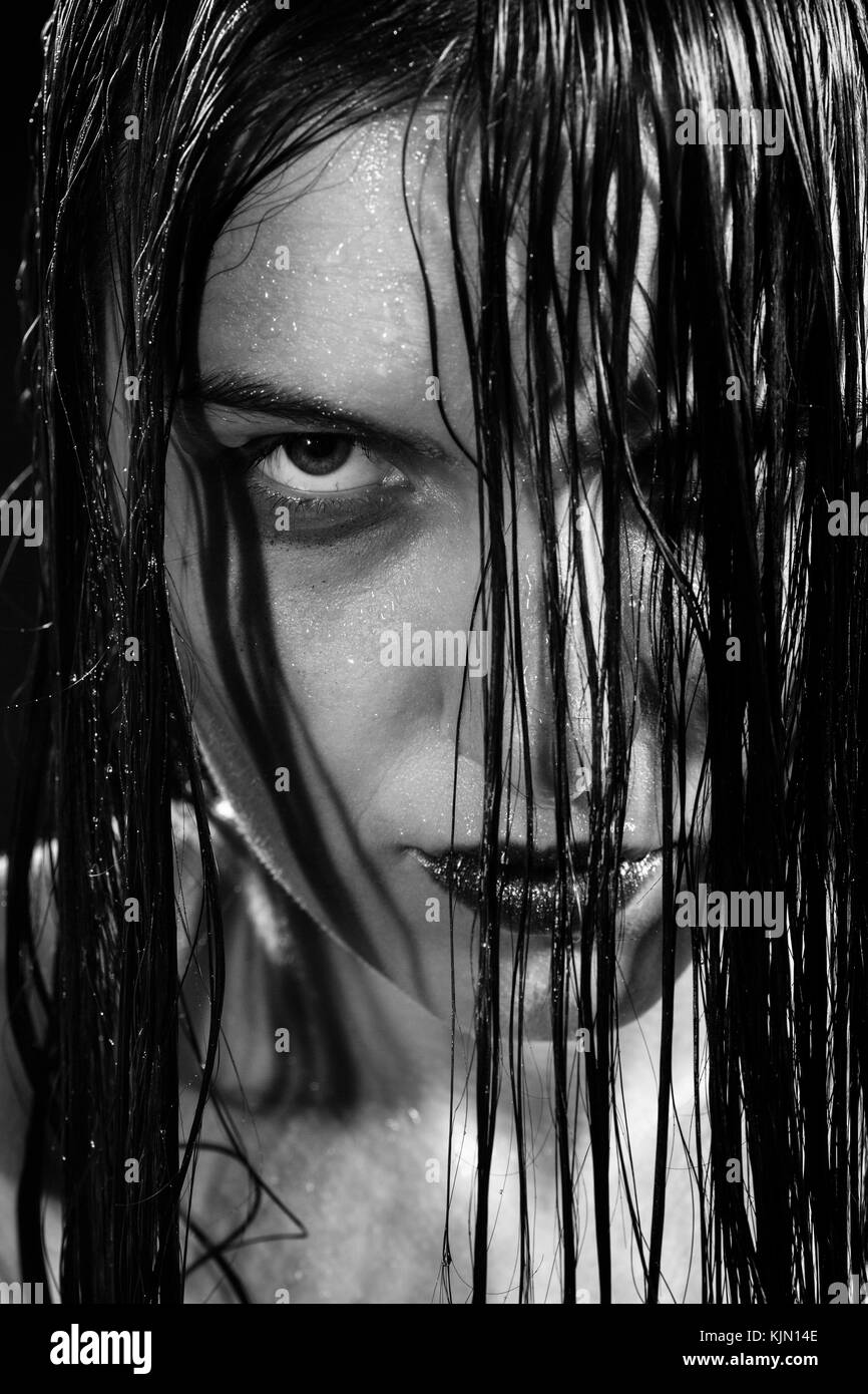 serious angry woman with wet black hair looking at camera, monochrome ...