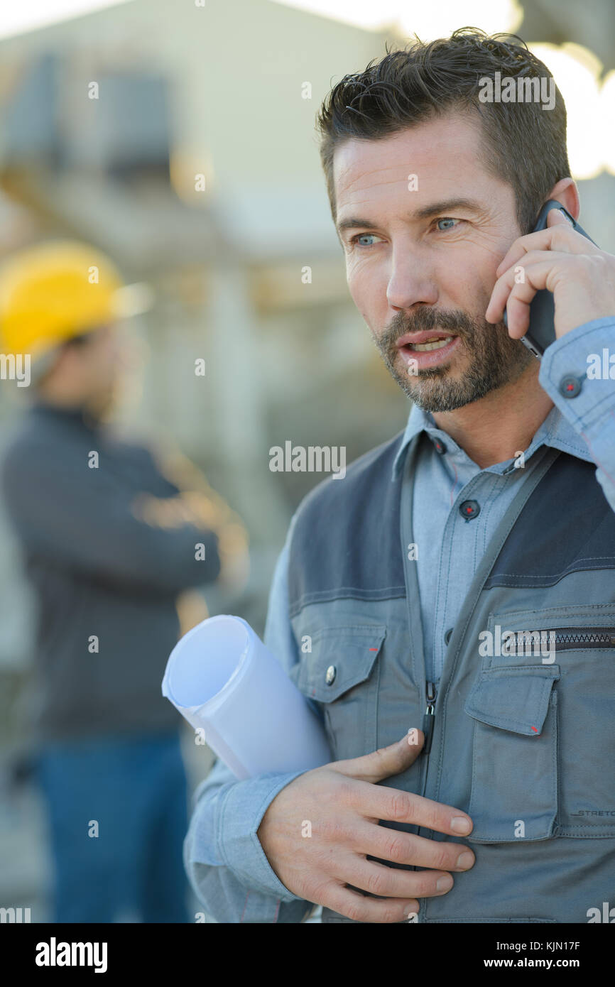 man calling with a cell phone outise factory Stock Photo - Alamy