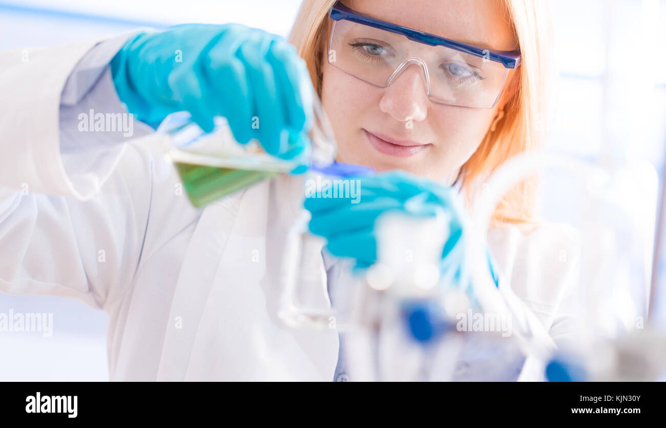 Female laboratory assistant with chemical experiment in scientific ...