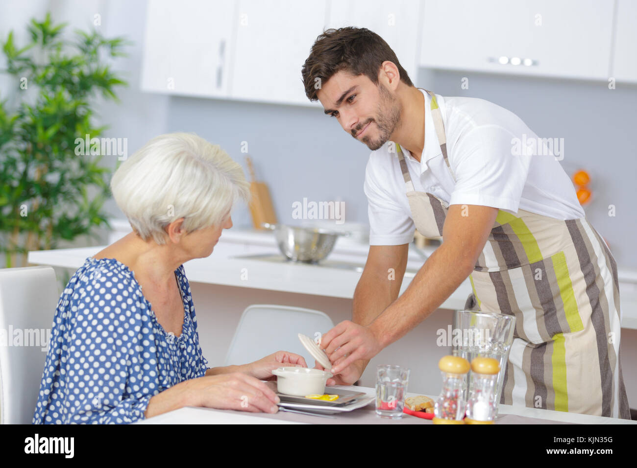 carer serving lunch to senior woman Stock Photo - Alamy