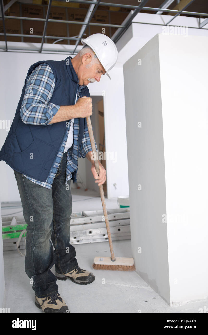 construction worker sweeping dust with broome at construction site ...