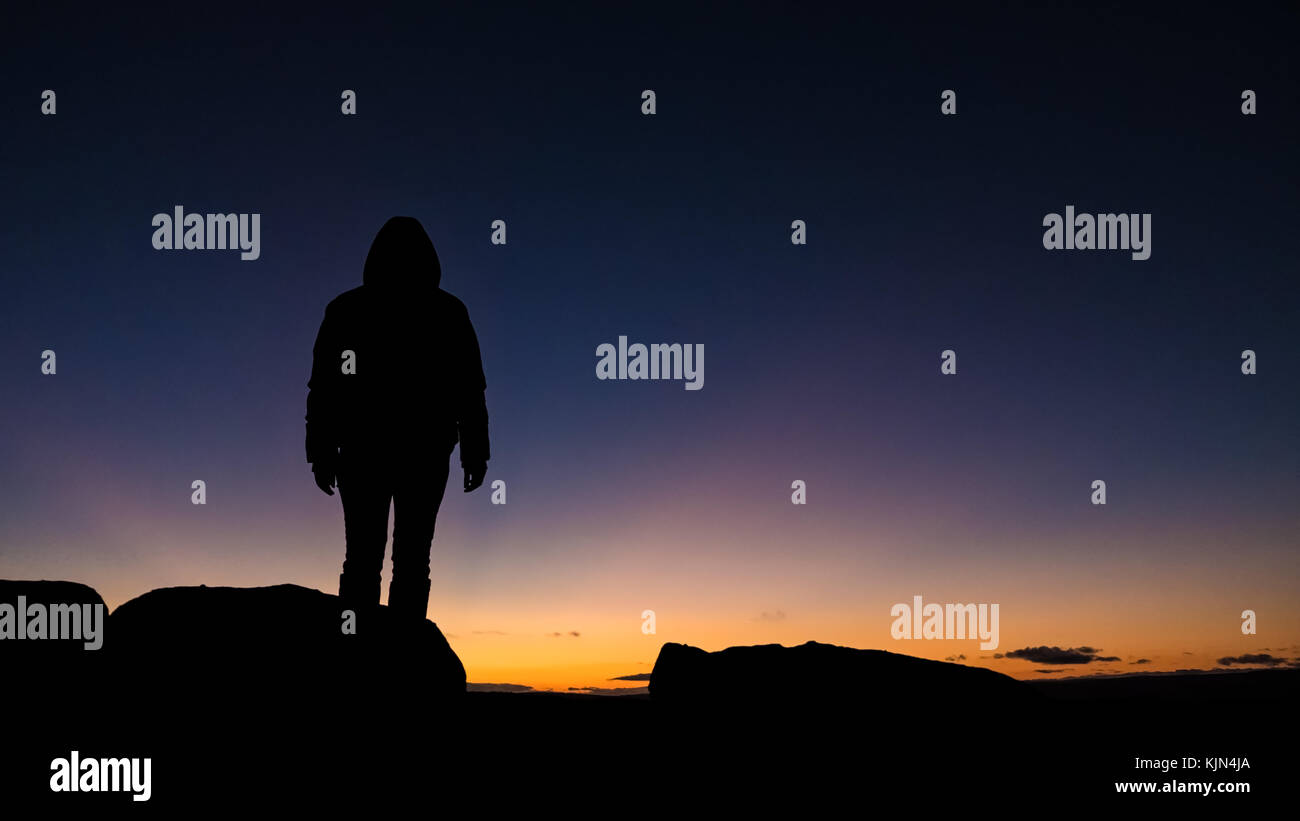 Standing on a stone outcrop, looking out over a valley at sunset Stock ...