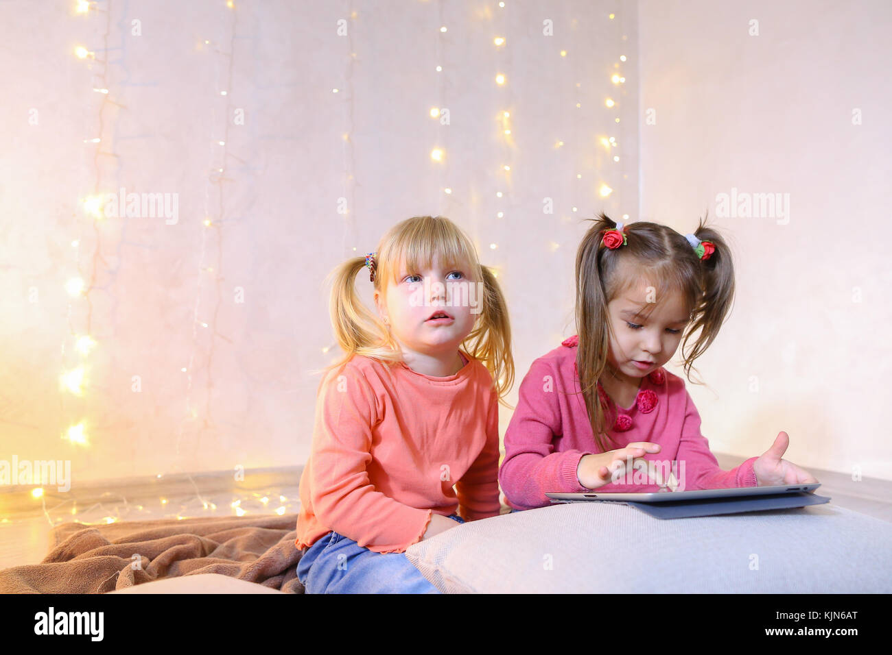 Little girls involved in use of tablet and sit on floor in brigh Stock ...