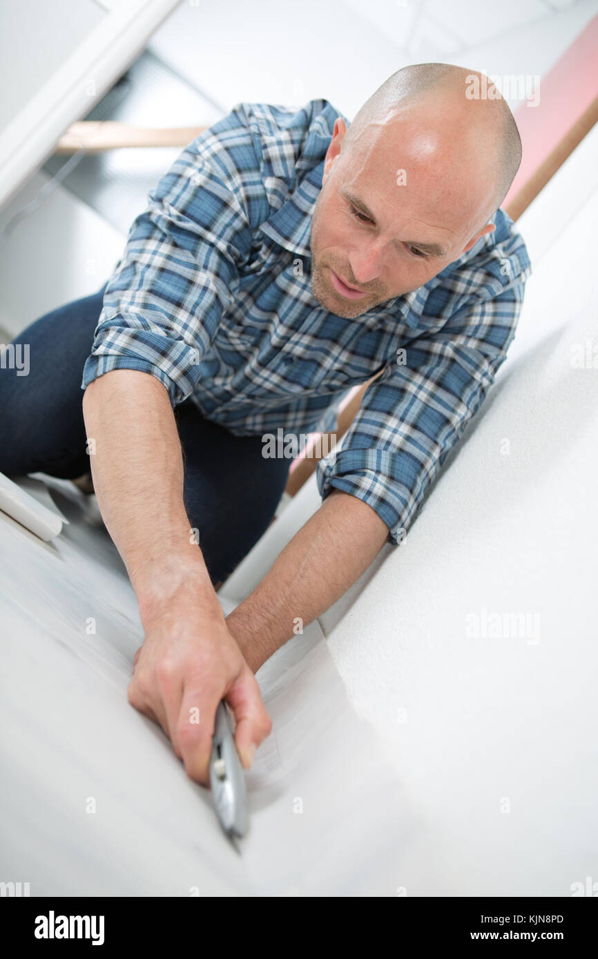 handyman fitting carpet while installation with cutter Stock Photo - Alamy