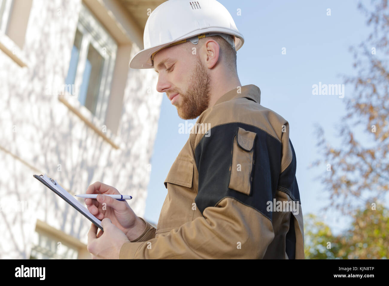 Contractor making notes outside residential building Stock Photo - Alamy