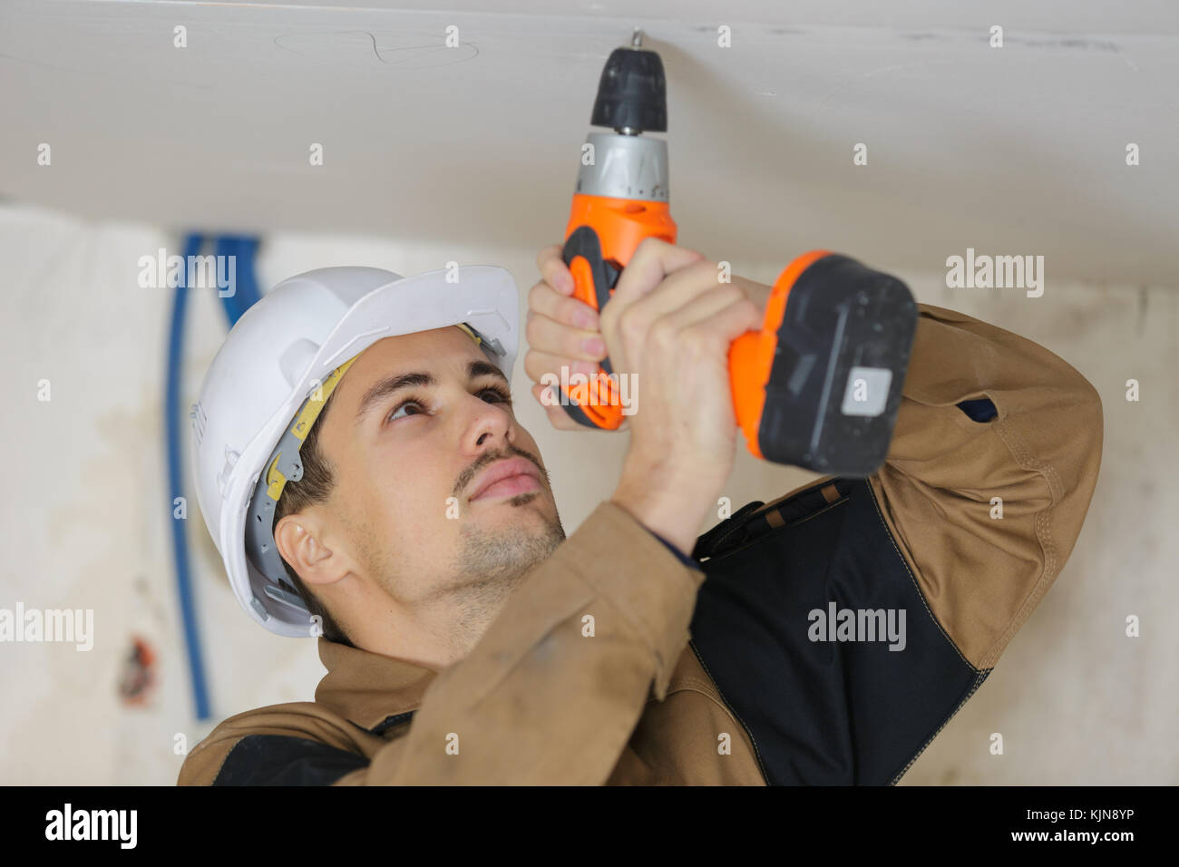 Workman drilling into ceiling Stock Photo - Alamy