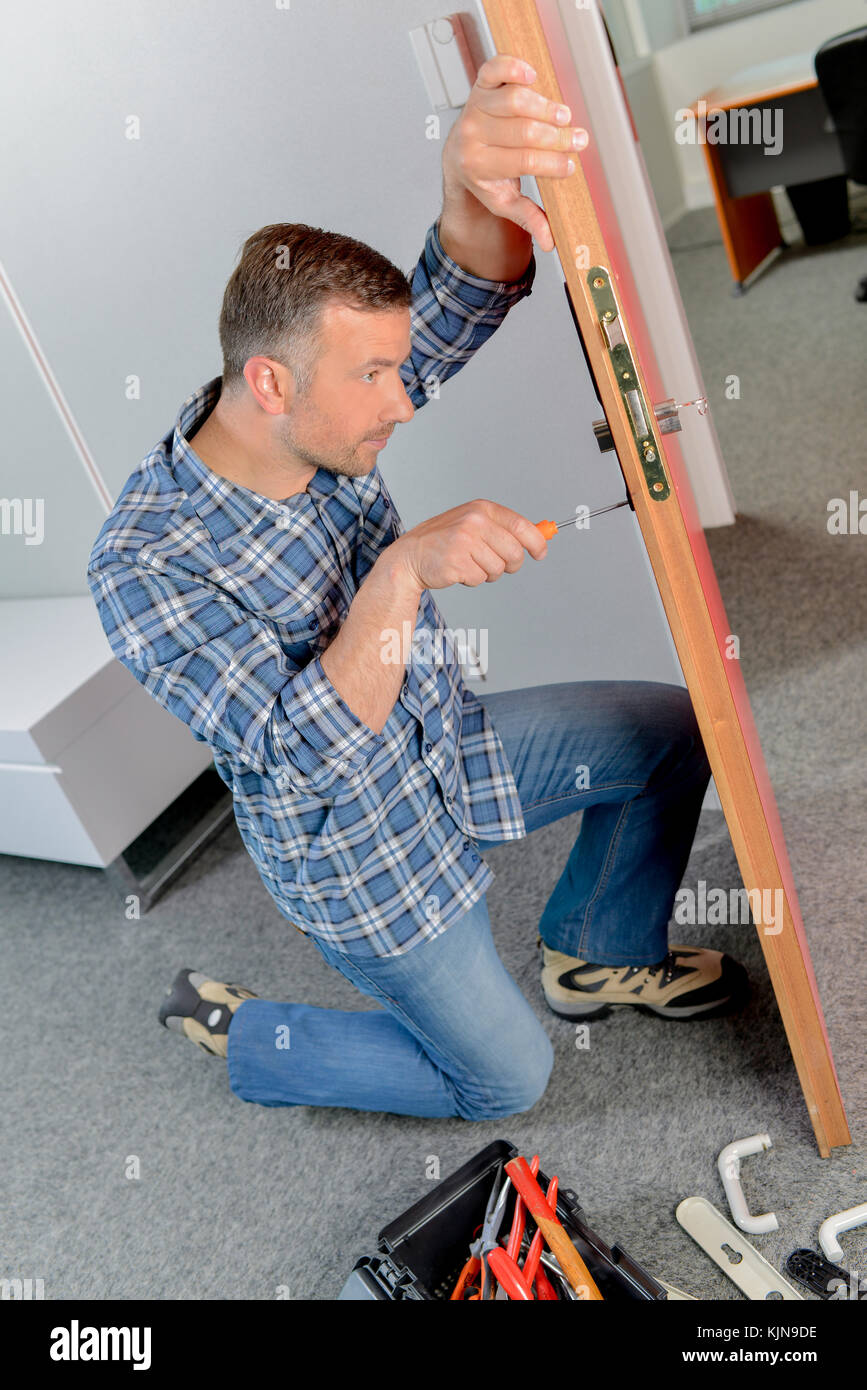 Man fixing lock to interior door Stock Photo - Alamy