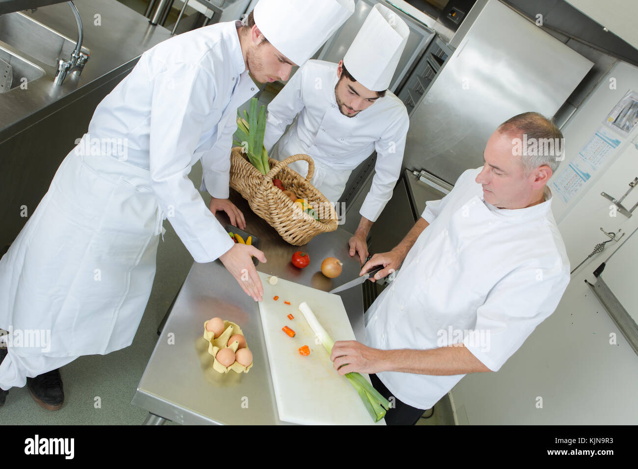 cook and apprentices at restaurant kitchen Stock Photo - Alamy