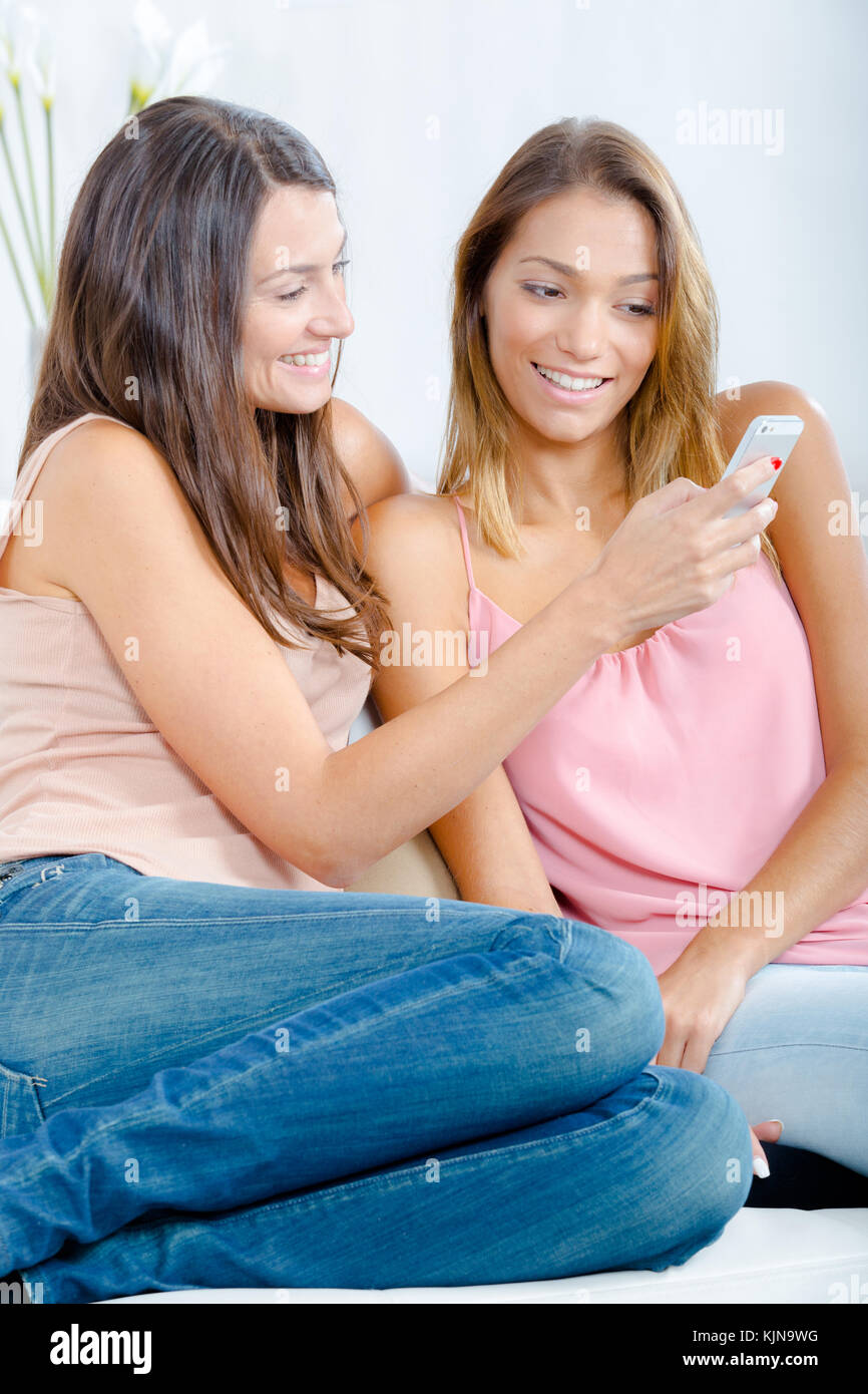 two roommates checking a smart-phone Stock Photo - Alamy