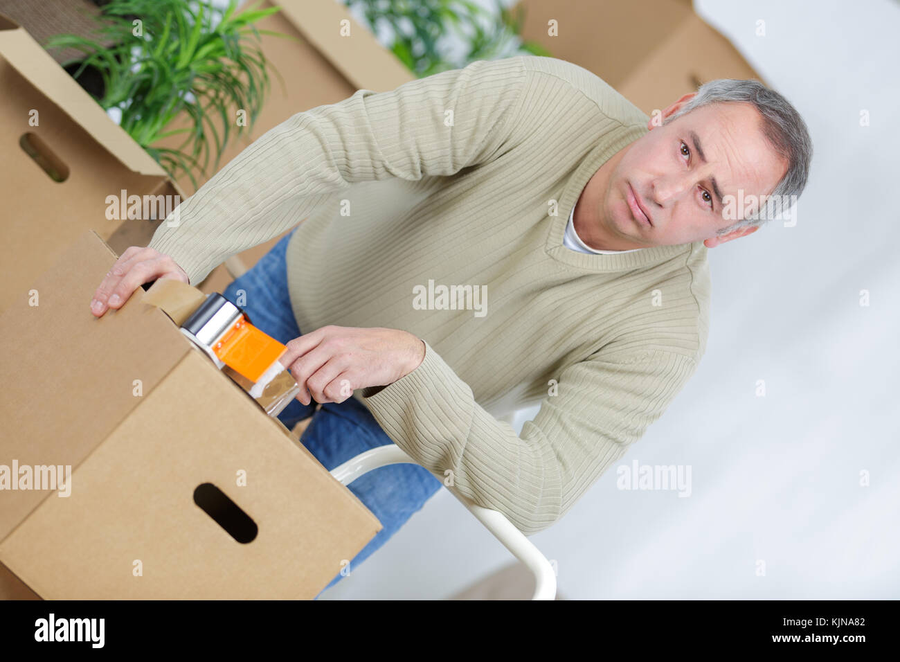 Depressed man packing cardboard boxes Stock Photo - Alamy