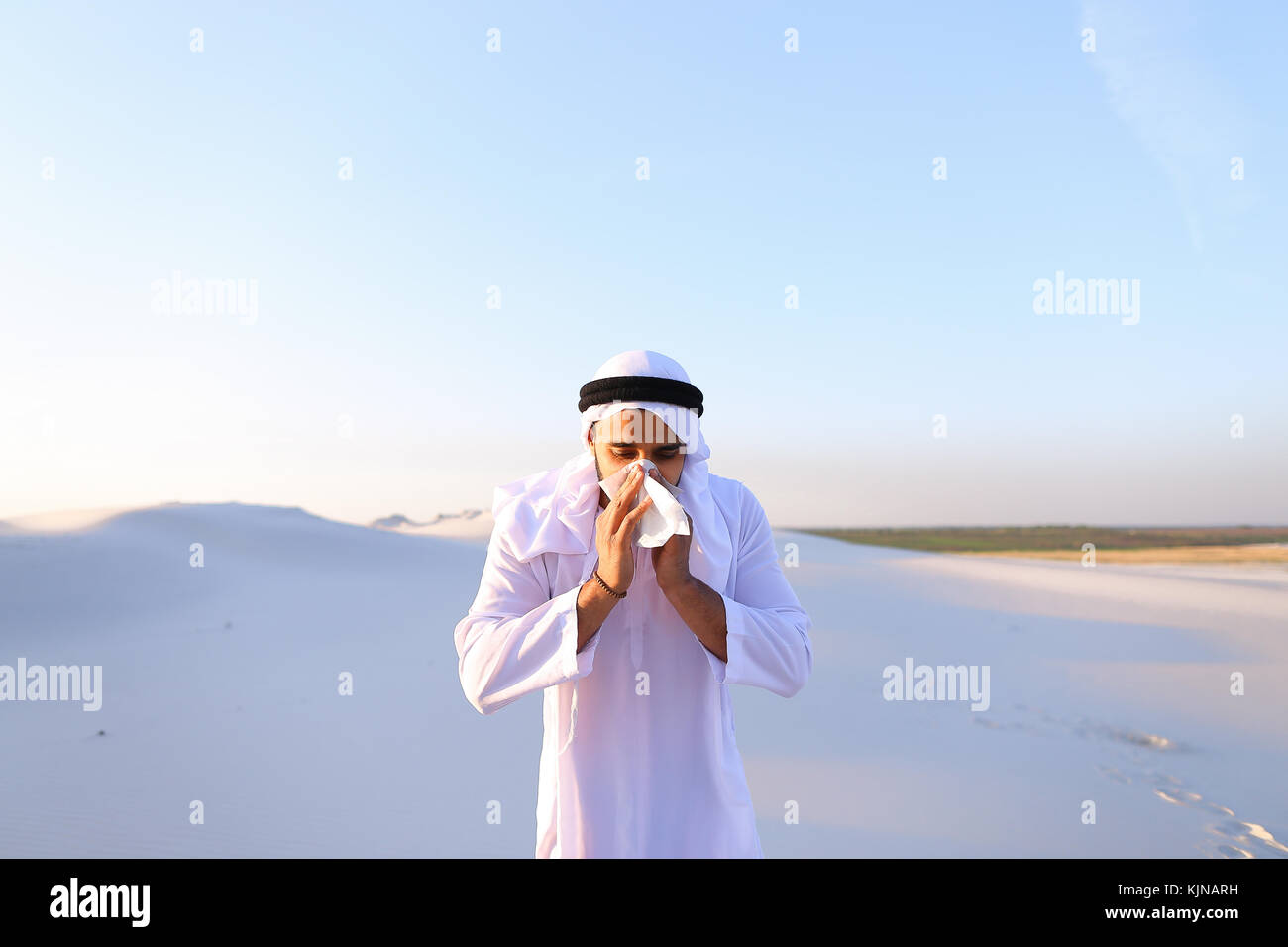 Arabian guy feels unpleasant sensations with cold, standing in m Stock ...
