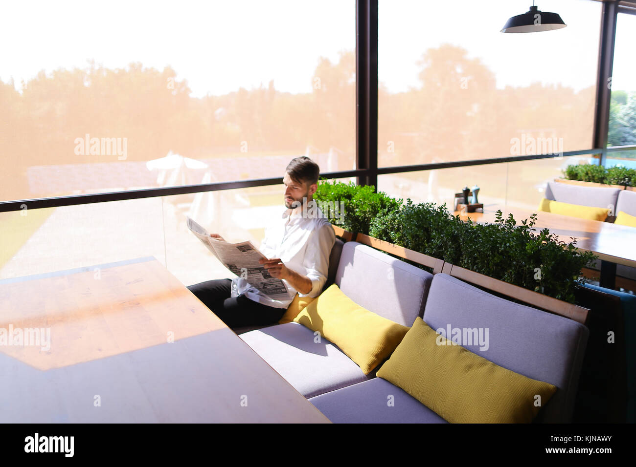 Prosperous man reading newspaper articles and resting Stock Photo - Alamy