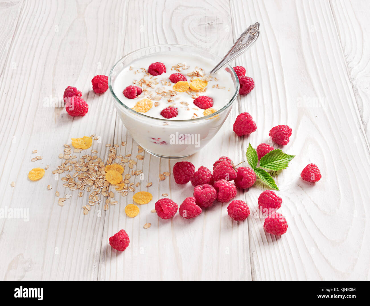 Bowl of homemade yogurt with muesli and fresh raspberry on wooden table ...