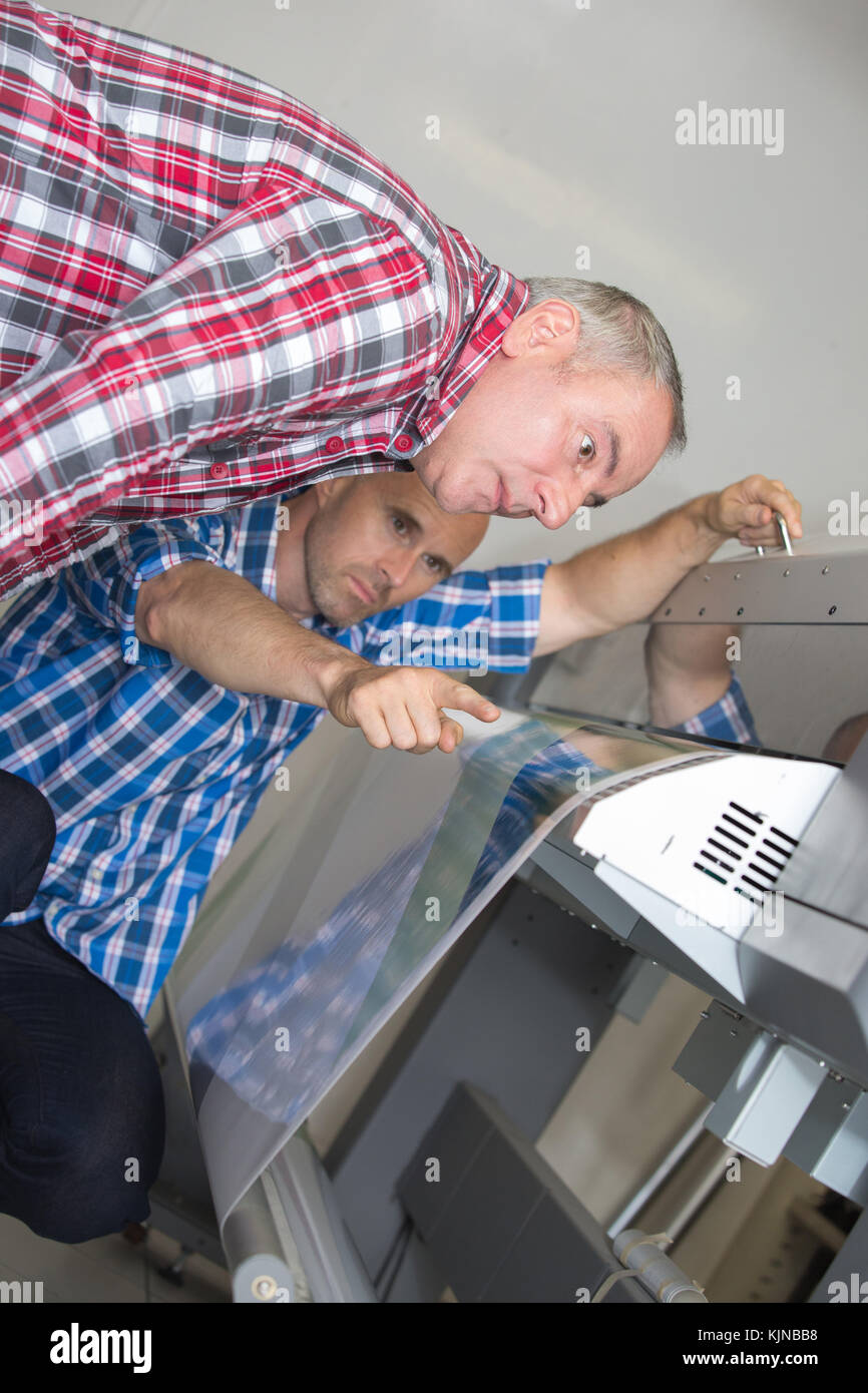 Men examining machine Stock Photo - Alamy