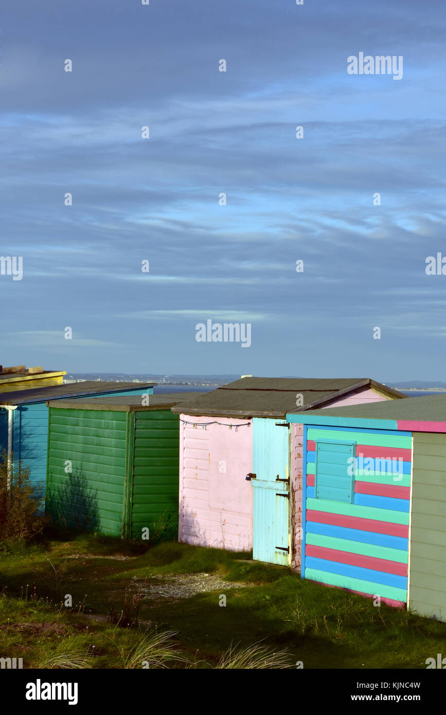 a row of colourful painted beach huts with an interesting cloud ...