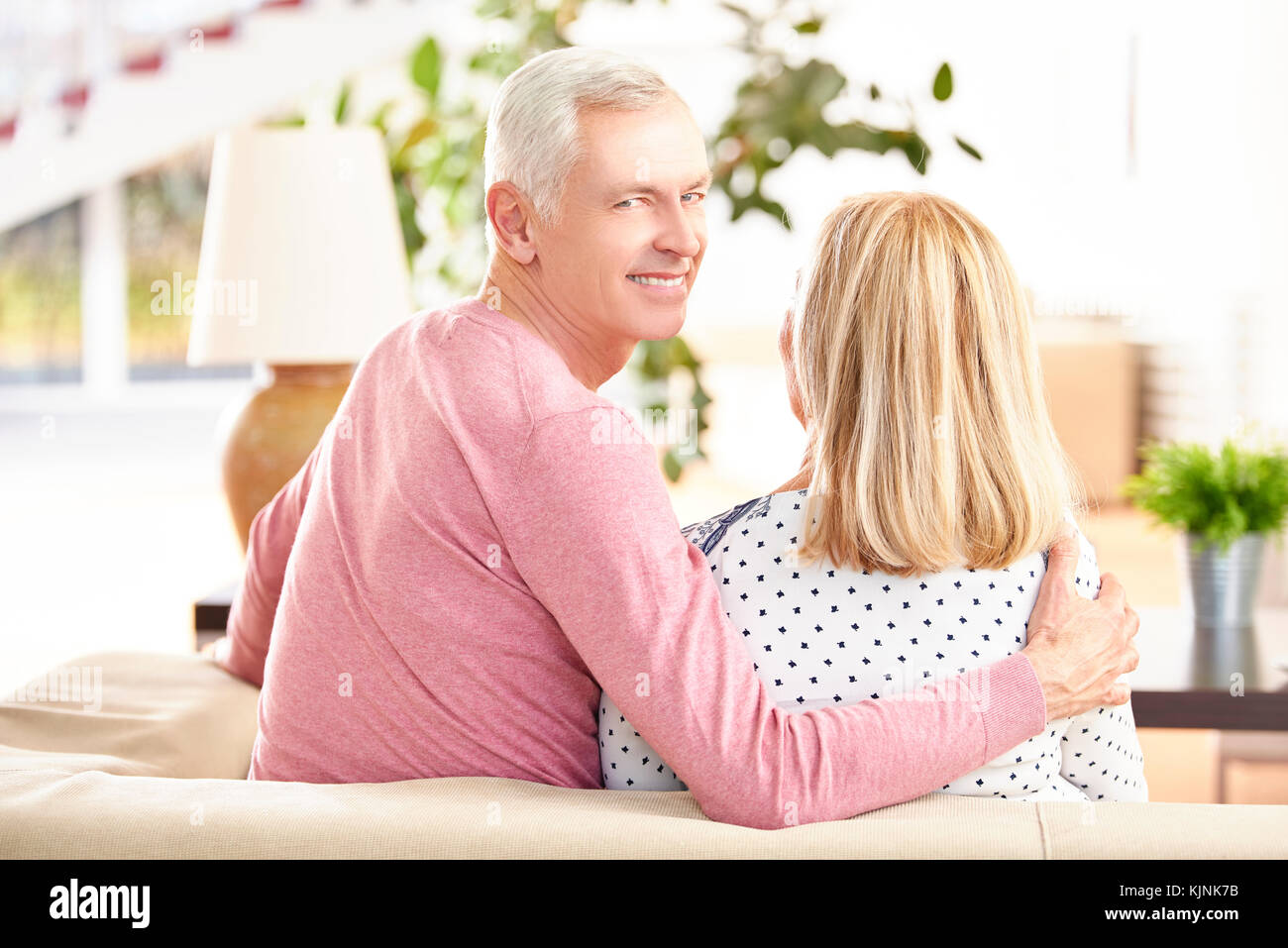 Rear view shot of a senior couple sitting on sofa at home while elderly ...