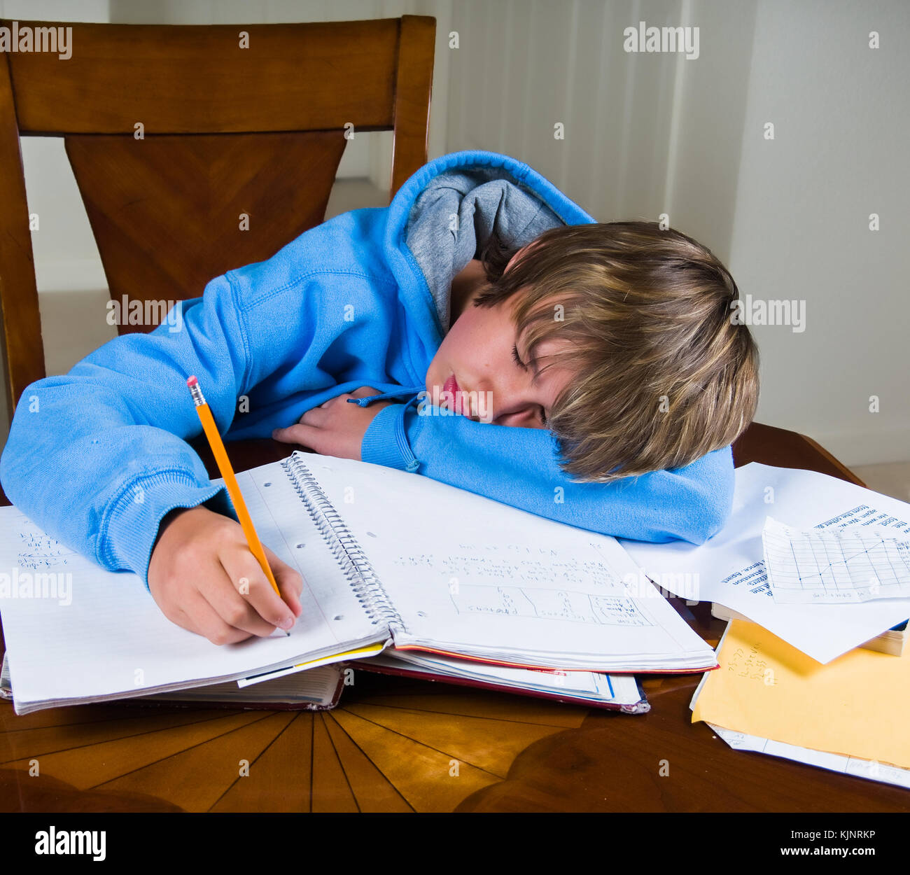 A young teenage boy falls asleep while doing a stack of homework from ...